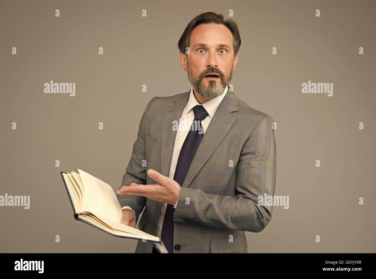 Senior school teacher in formal suit point hand at open book with ...