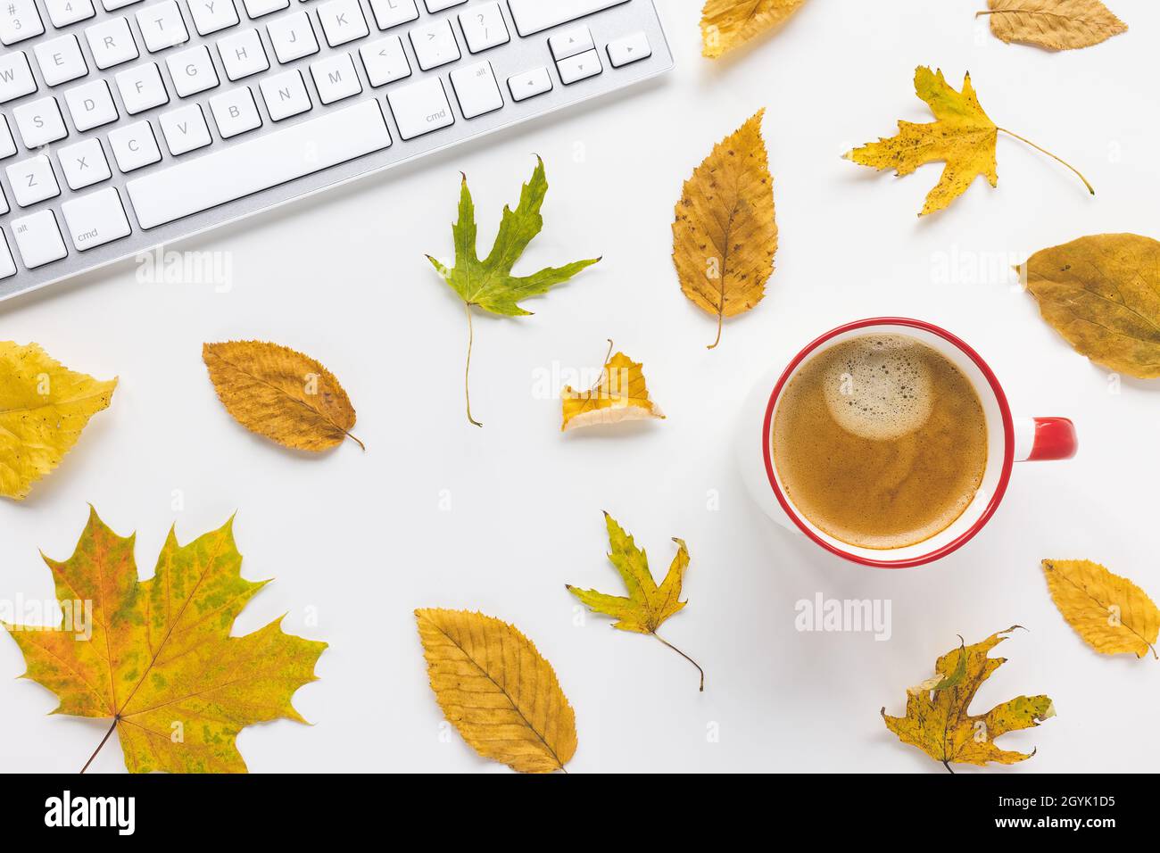 Computer keyboard, cup of espresso with crema and yellow fall leaves on ...
