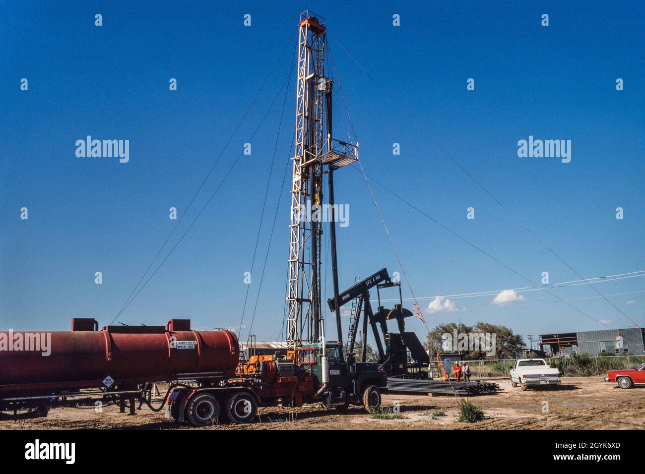 A pulling unit crew pulls the sucker rods out of an existing oil well ...