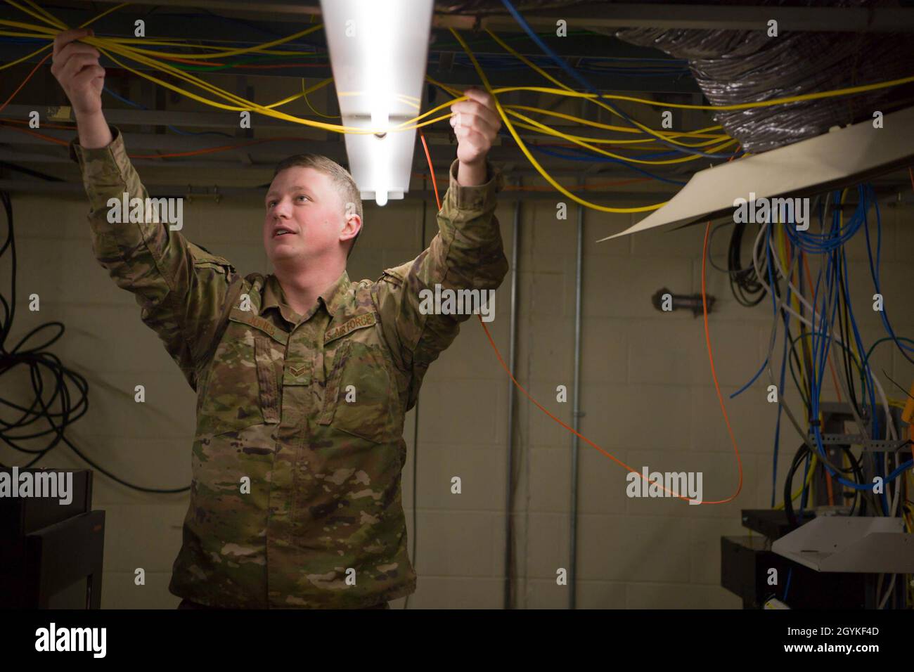 An airman assigned to the 5th Communications Squadron adjusts wires at ...