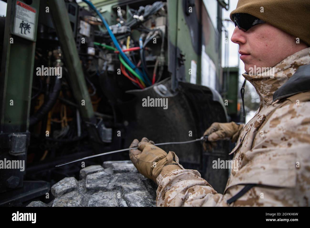 U.S. Marine Corps Lance Cpl. Donald Honsaker checks the oil on a 7-ton ...