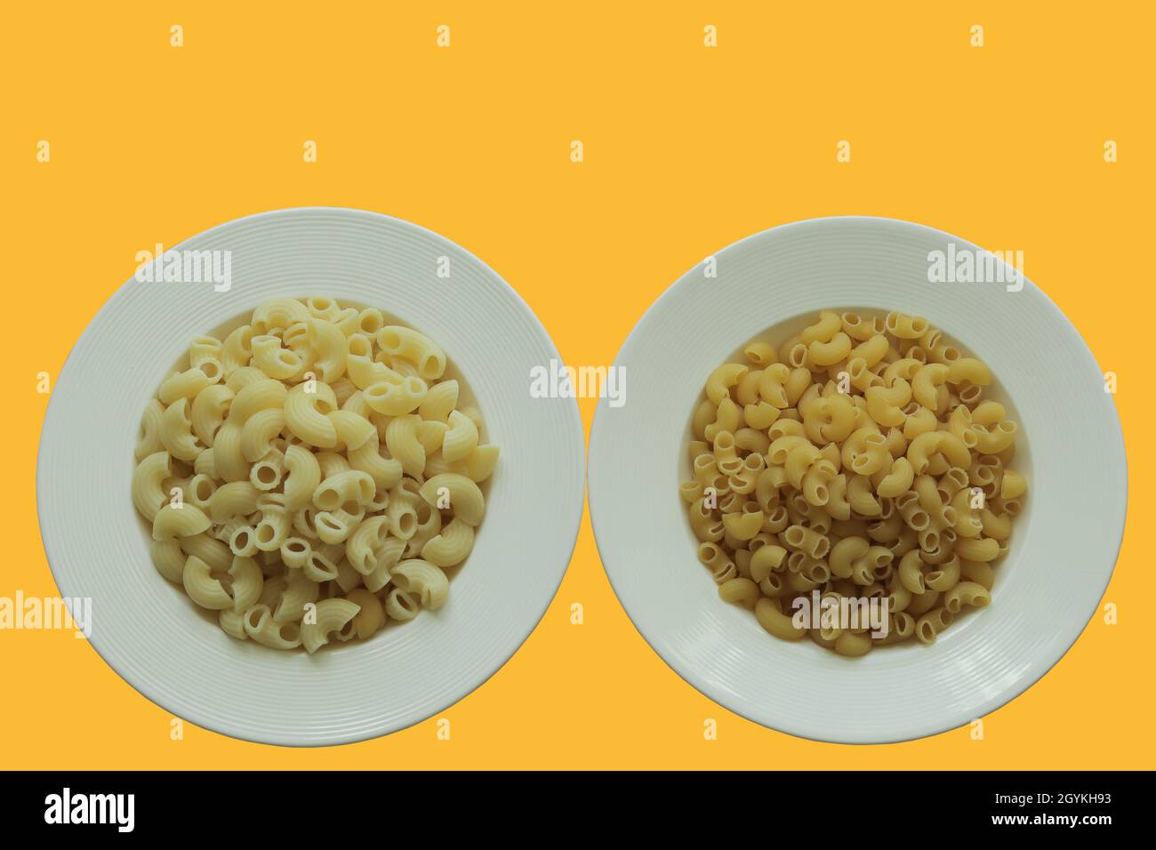 Top view cooked and uncooked macaroni on white round plate and ...