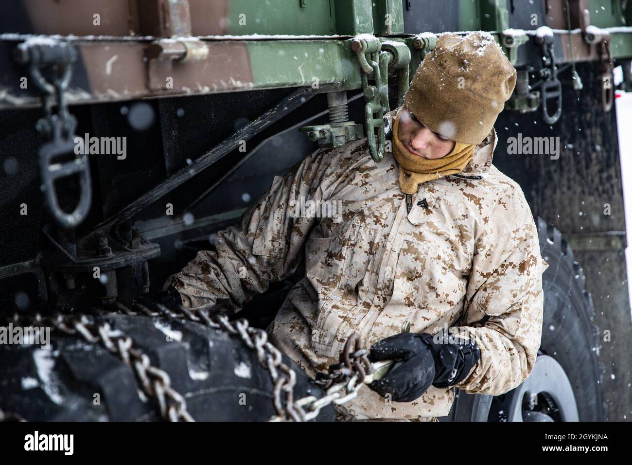 U.S. Marine Corps Cpl. Vincent Johnson pulls a snow chain over a tire ...