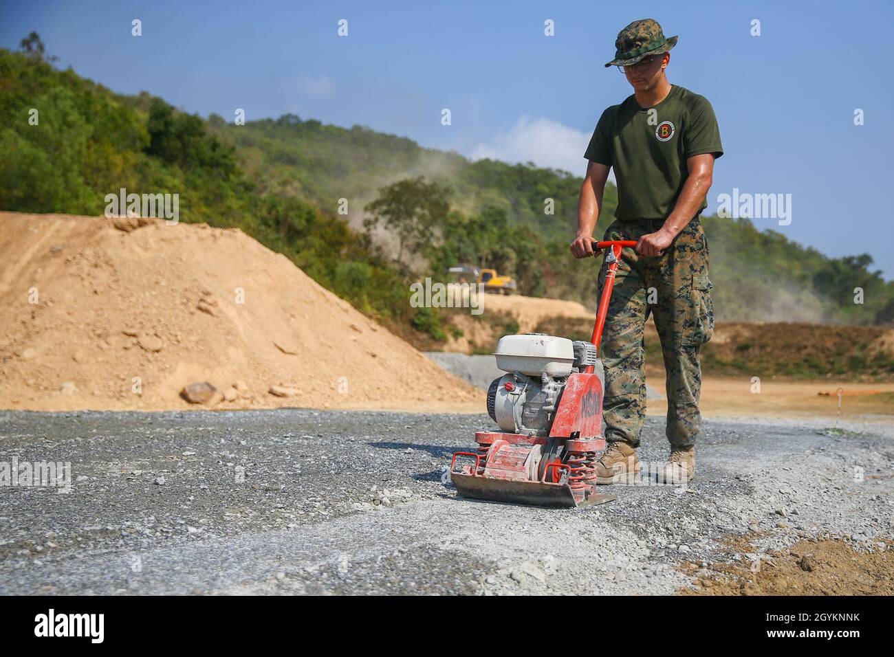 U.S. Marine Corps Lance Cpl. Alex Moulzolf pushes a vibratory compactor ...
