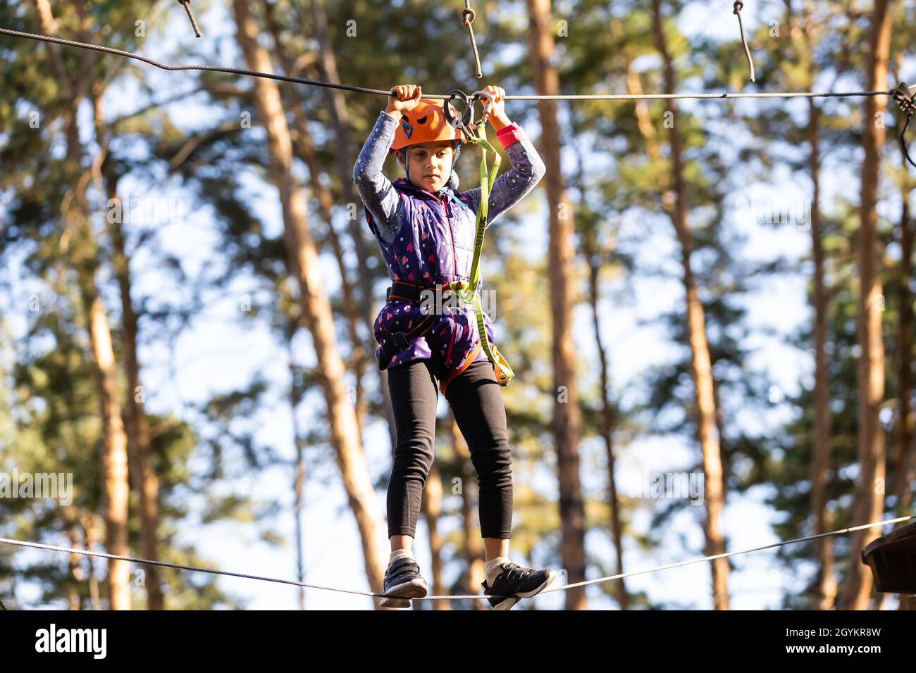 Little girl is standing on a rope, holding a rope with his hands. A ...