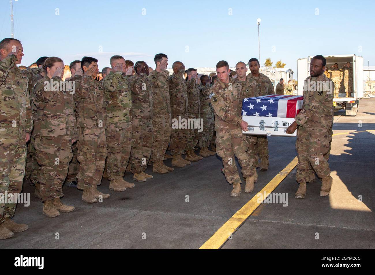 U.S. Soldiers carry a flag-draped transfer case holding the remains of ...