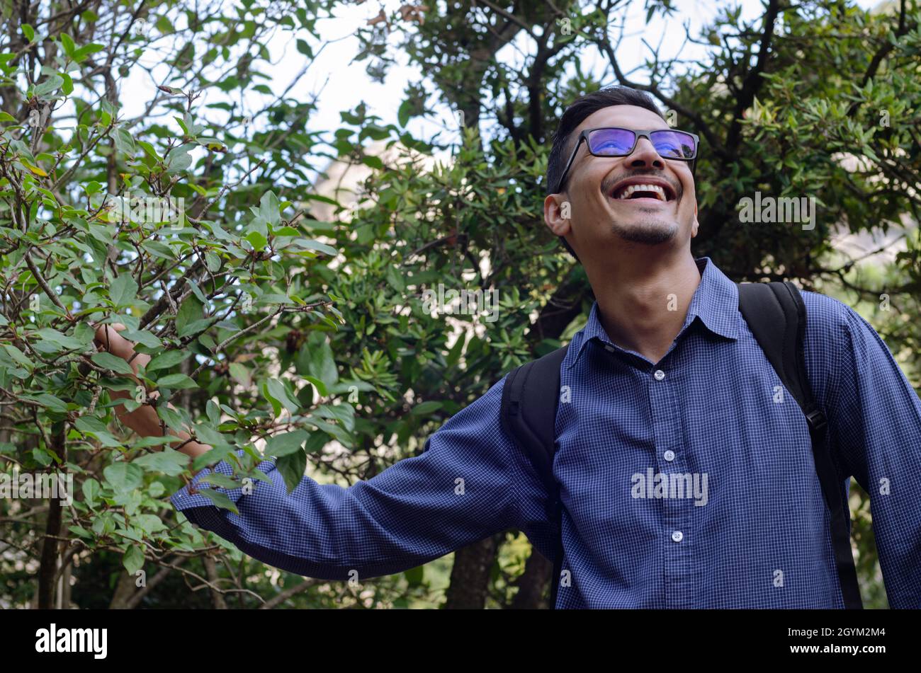 Man is standing among trees and bushes in the park. happy indian man ...