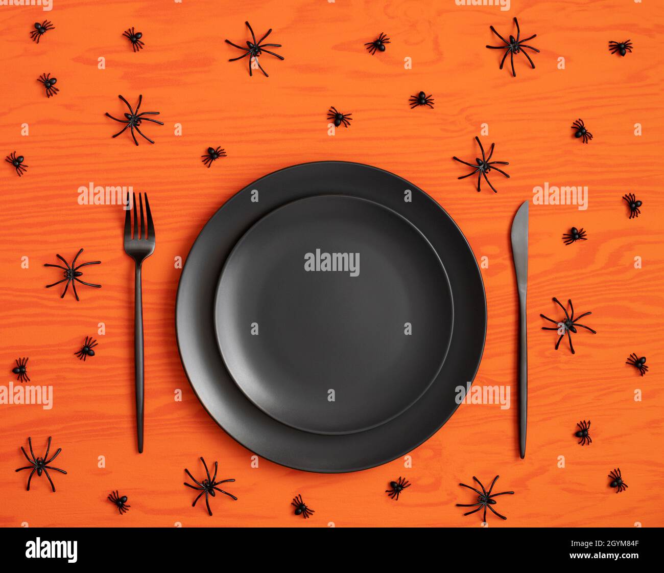 Halloween table setting. Empty black plate and cutlery, spiders on ...