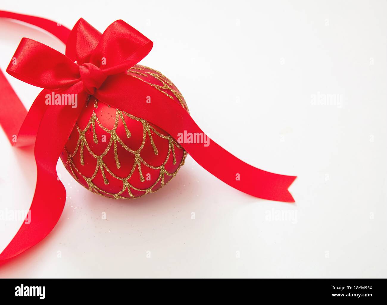 Christmas ball bauble with golden glitter and tied red ribbon bow ...