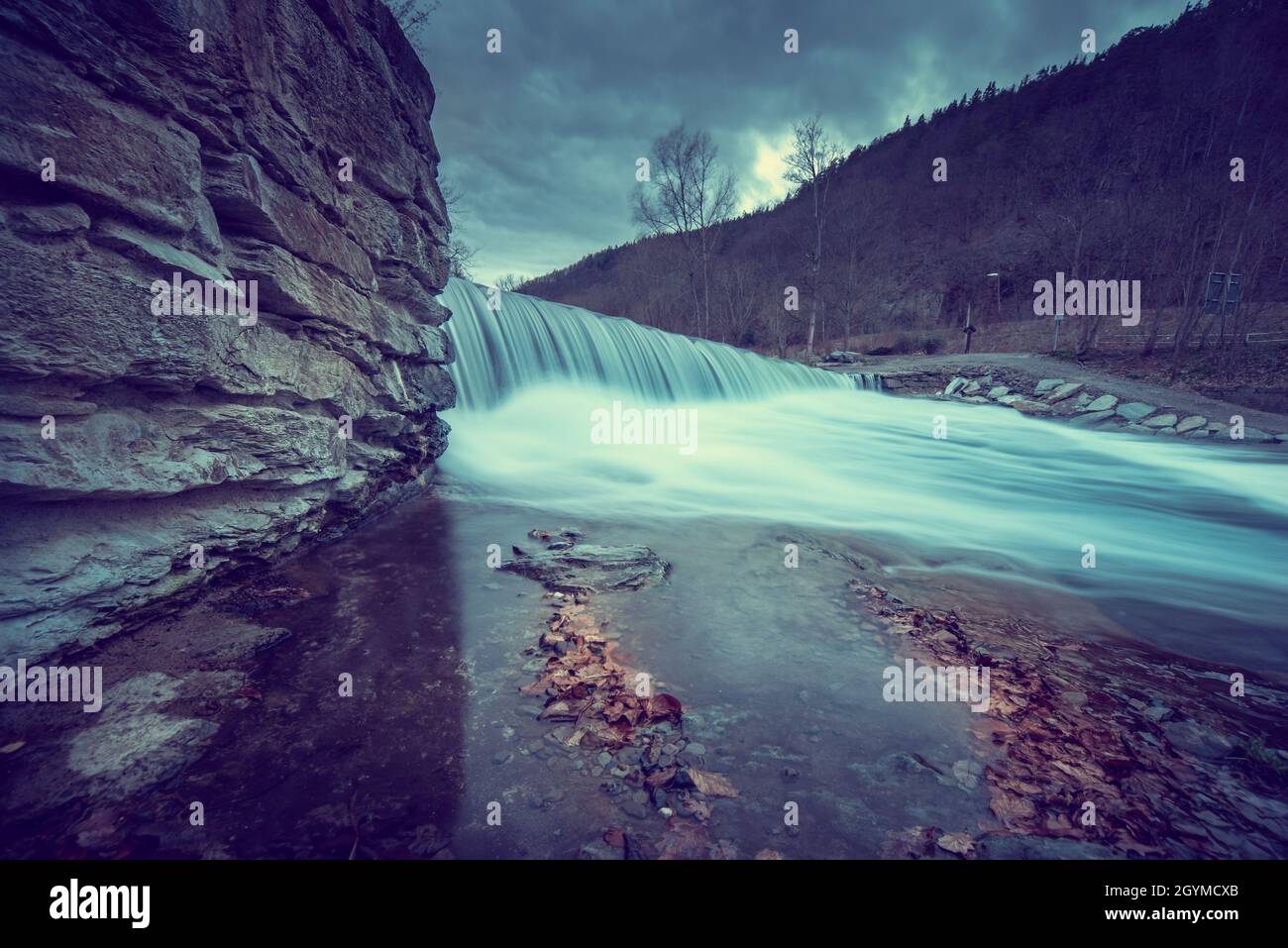 Mesmerizing view of a waterfall between the stone wall and a hill ...