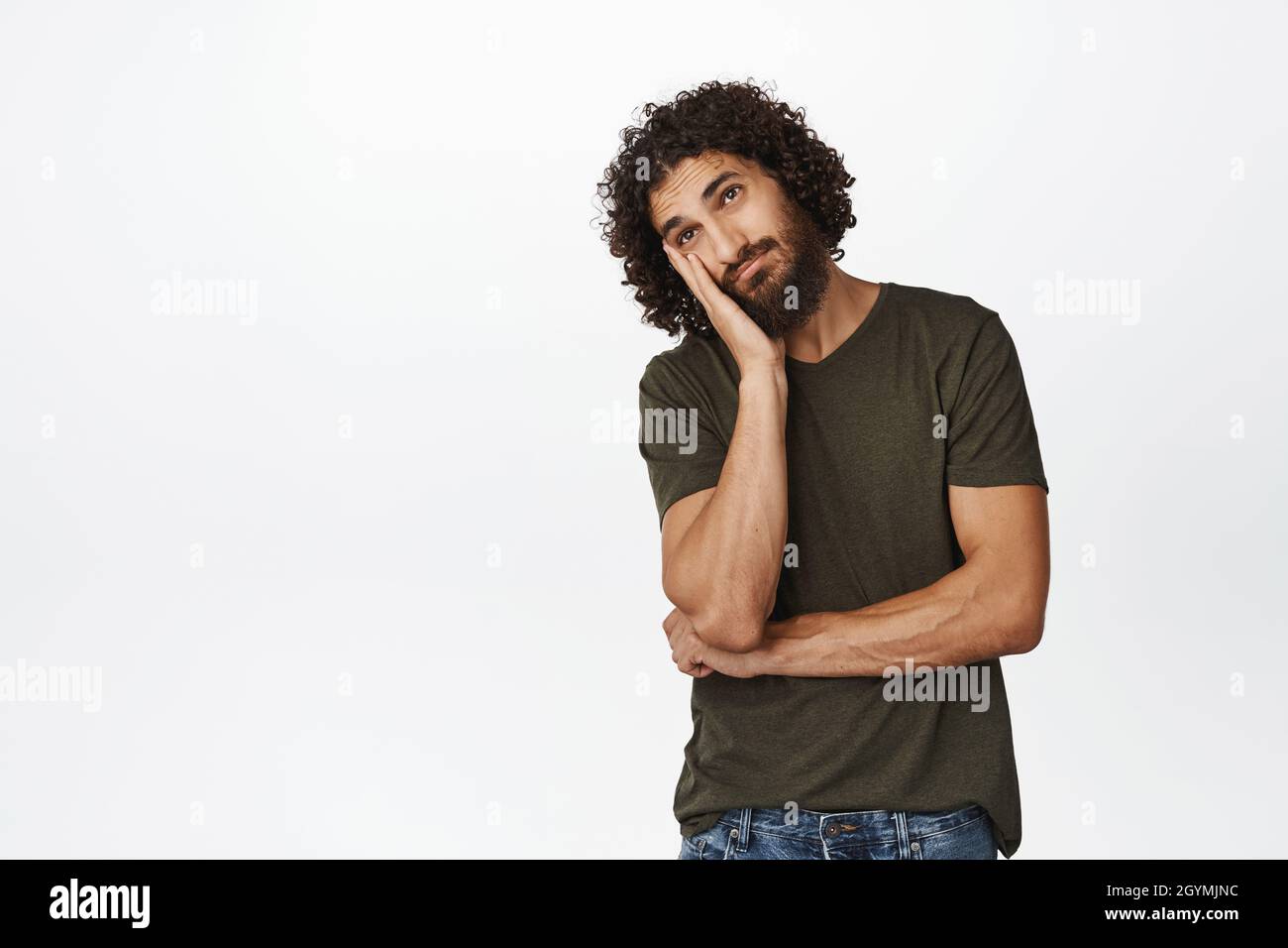 Sad and bored curly guy lean on hand, staring reluctant and unamused ...