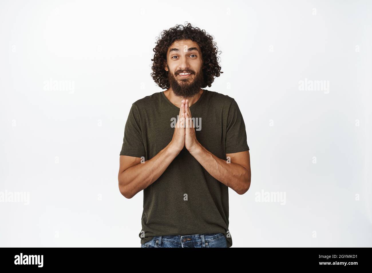 Portrait of curly guy asking for help, begging, holding hands in ...