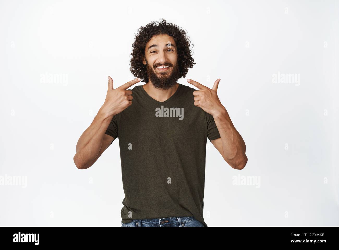 Happy hispanic man with beard, pointing fingers at his smile, smiling ...