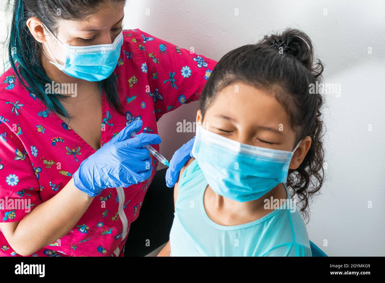 children's nurse injecting brown girl's arm. doctor injecting covid-19 ...