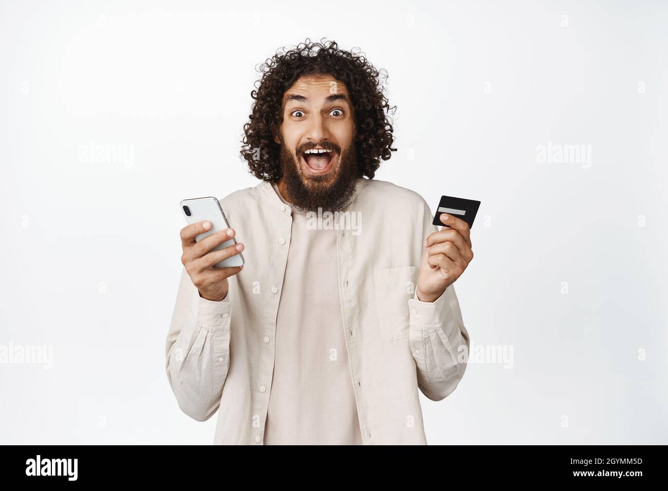 Enthusiastic male model screaming, holding mobile phone and credit card ...