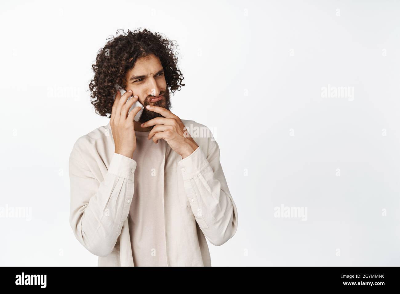 Thoughtful hispanic man talking on mobile phone, thinking on call ...