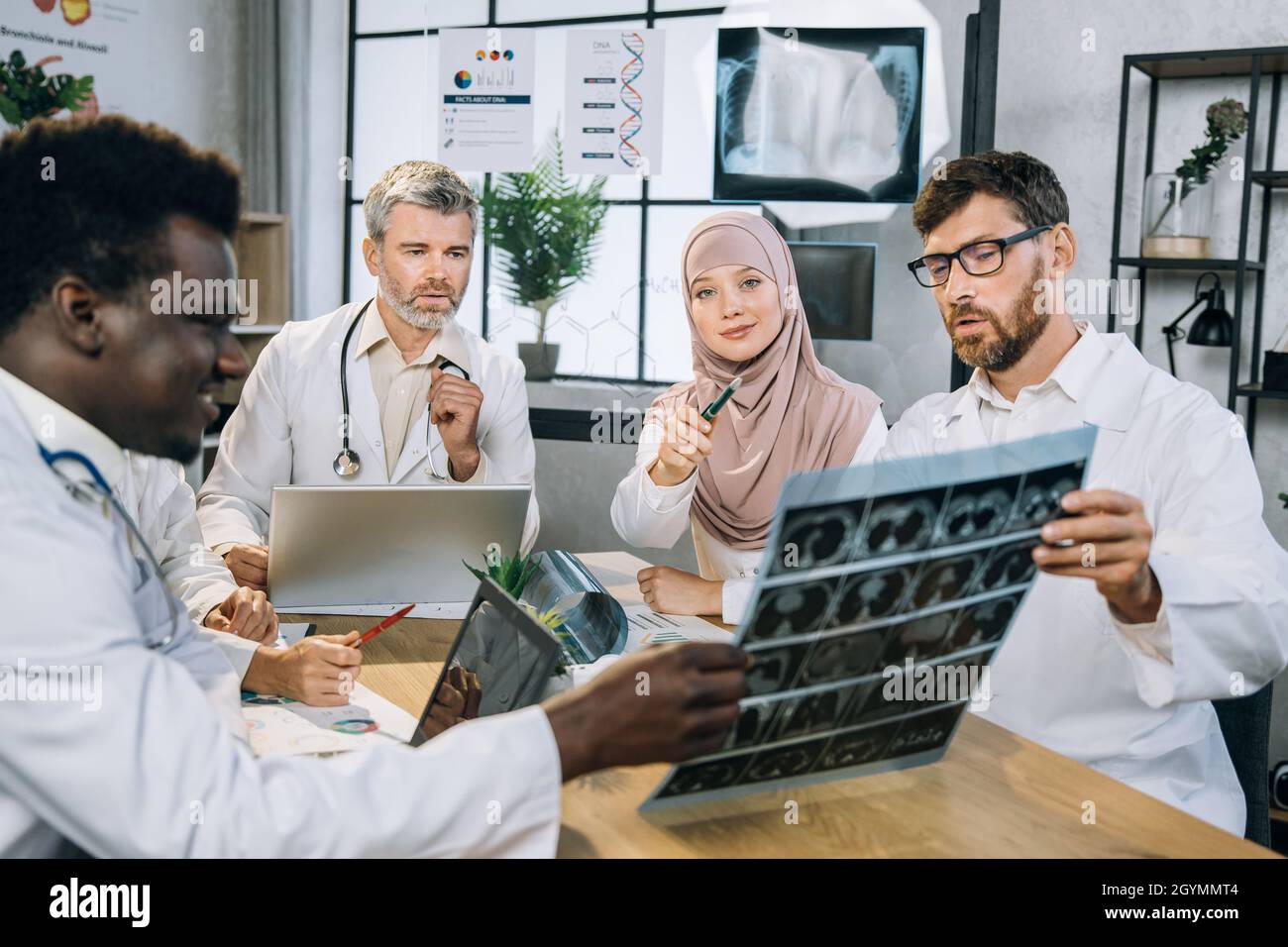 Competent multiracial doctors with modern gadgets on table examining x ...