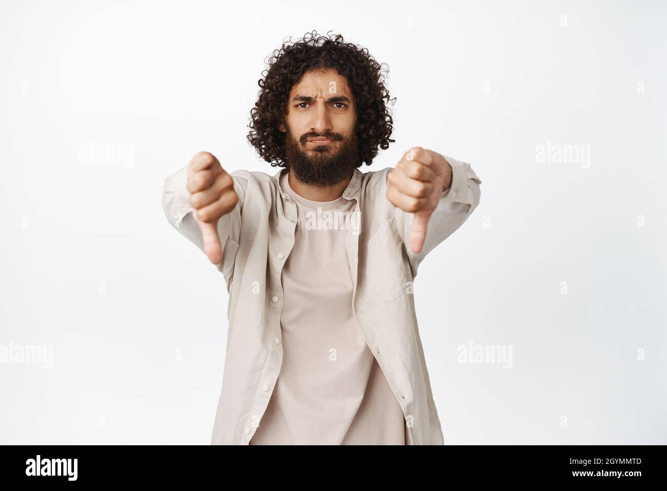Disappointed arab guy showing thumbs down and frowning upset, dislike ...
