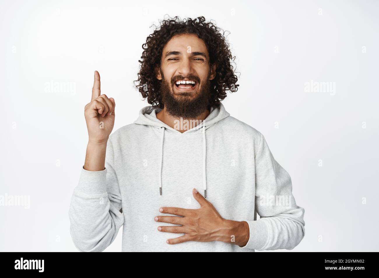 Carefree arab man laughing, pointing finger up and smiling, showing ...