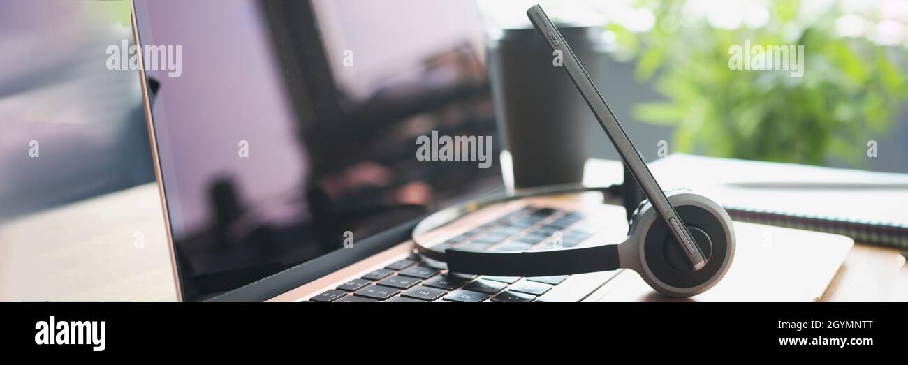 Headphones with microphone lying on laptop keyboard on desktop closeup ...