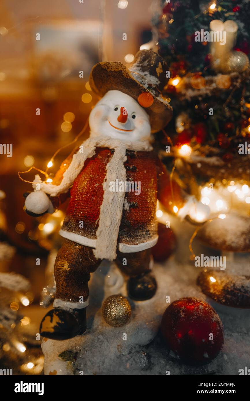 Funny winter toy snowman and Christmas tree branch with golden lights ...