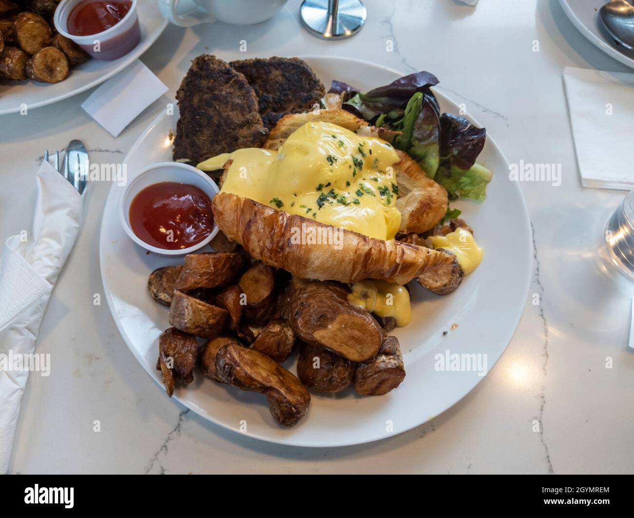 Top down view of a large breakfast spread of eggs benedict, fingerling ...