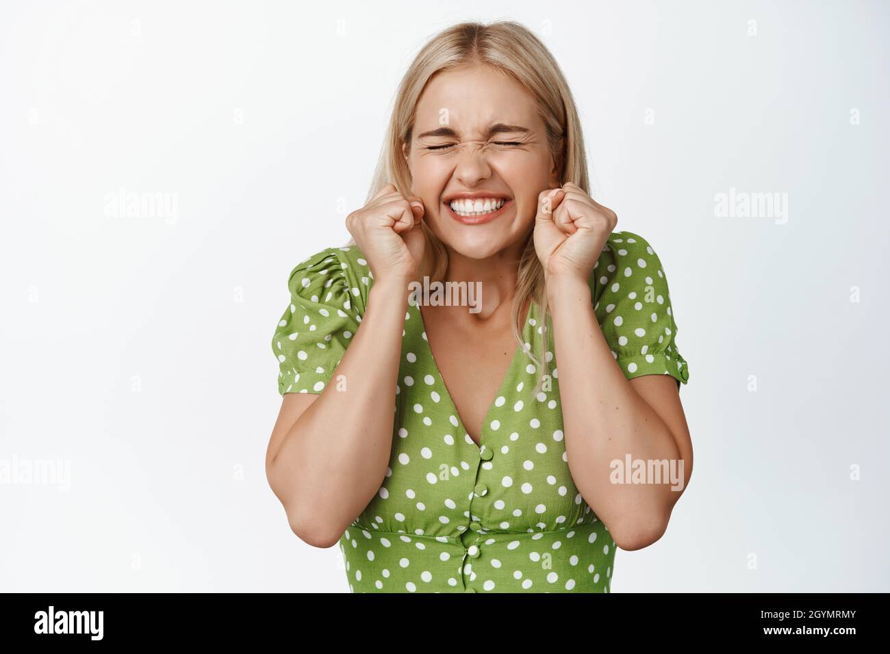 Enthusiastic blond girl relish something good, jumping and smiling with ...