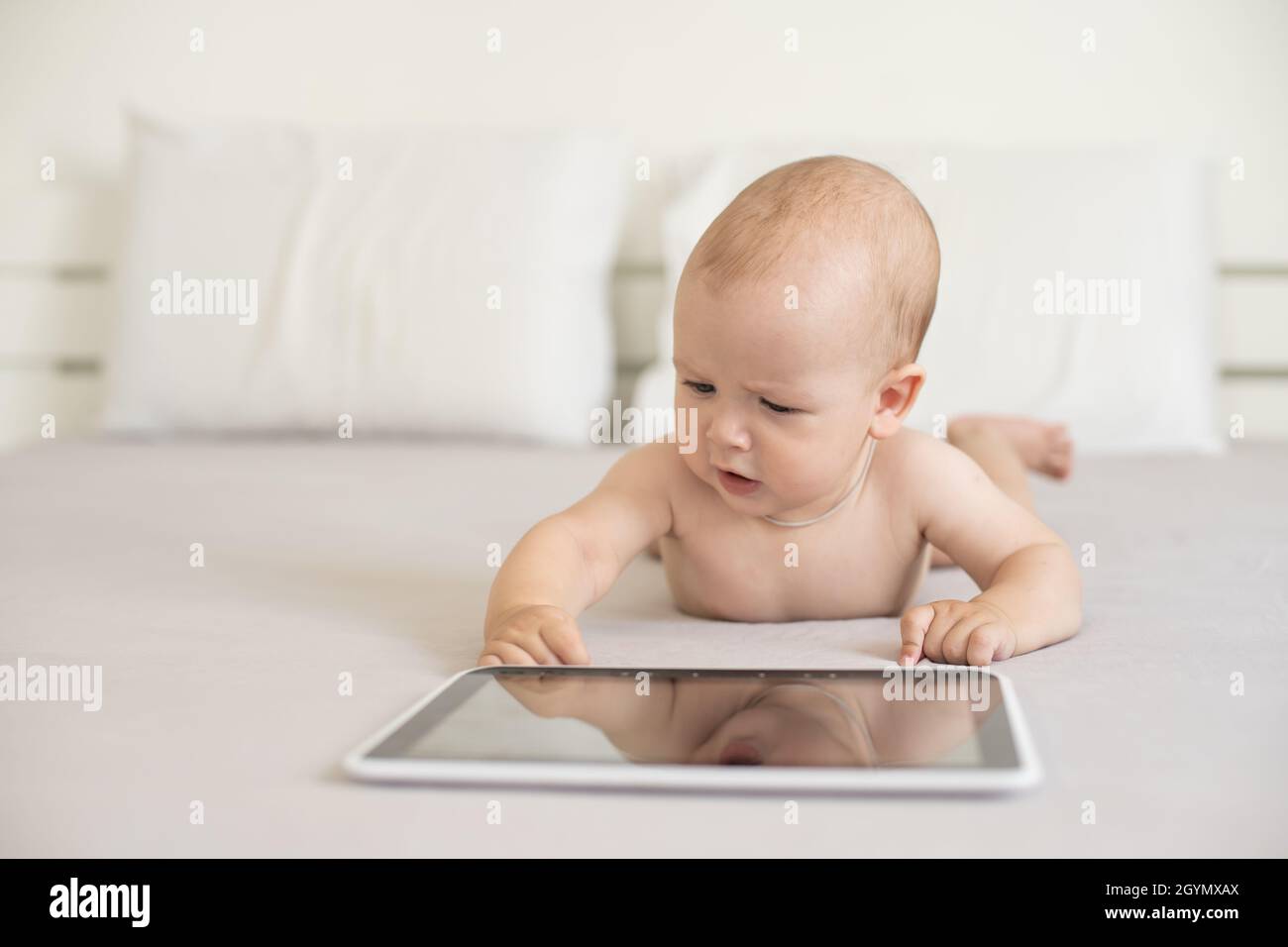 Happy Baby Looking At Digital Tablet While Lying On Bed Stock Photo - Alamy