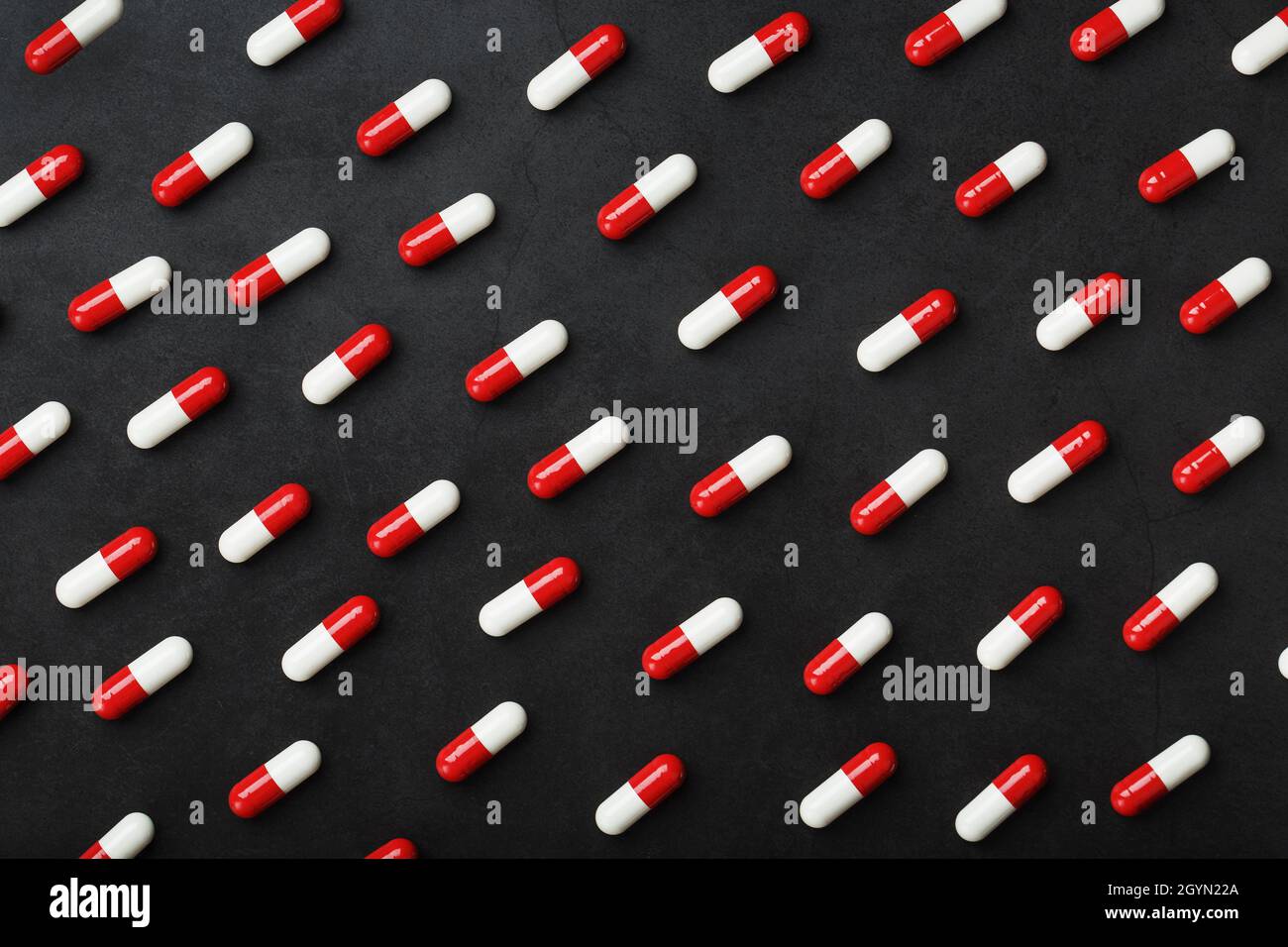 A pattern of red and white pills of medical pills on a black background ...