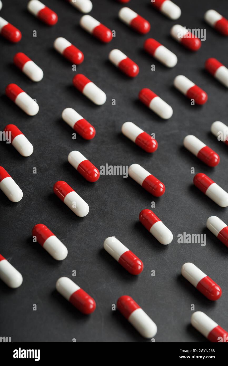 A pattern of red and white pills of medical pills on a black background ...