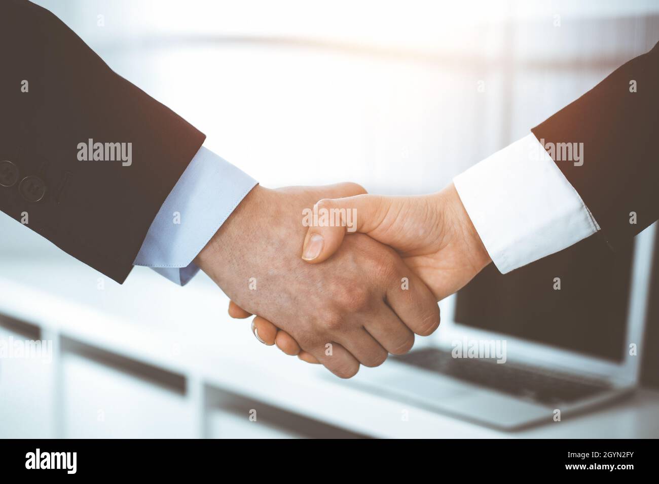 Businessman and woman shaking hands in sunny office, close-up. Concept ...