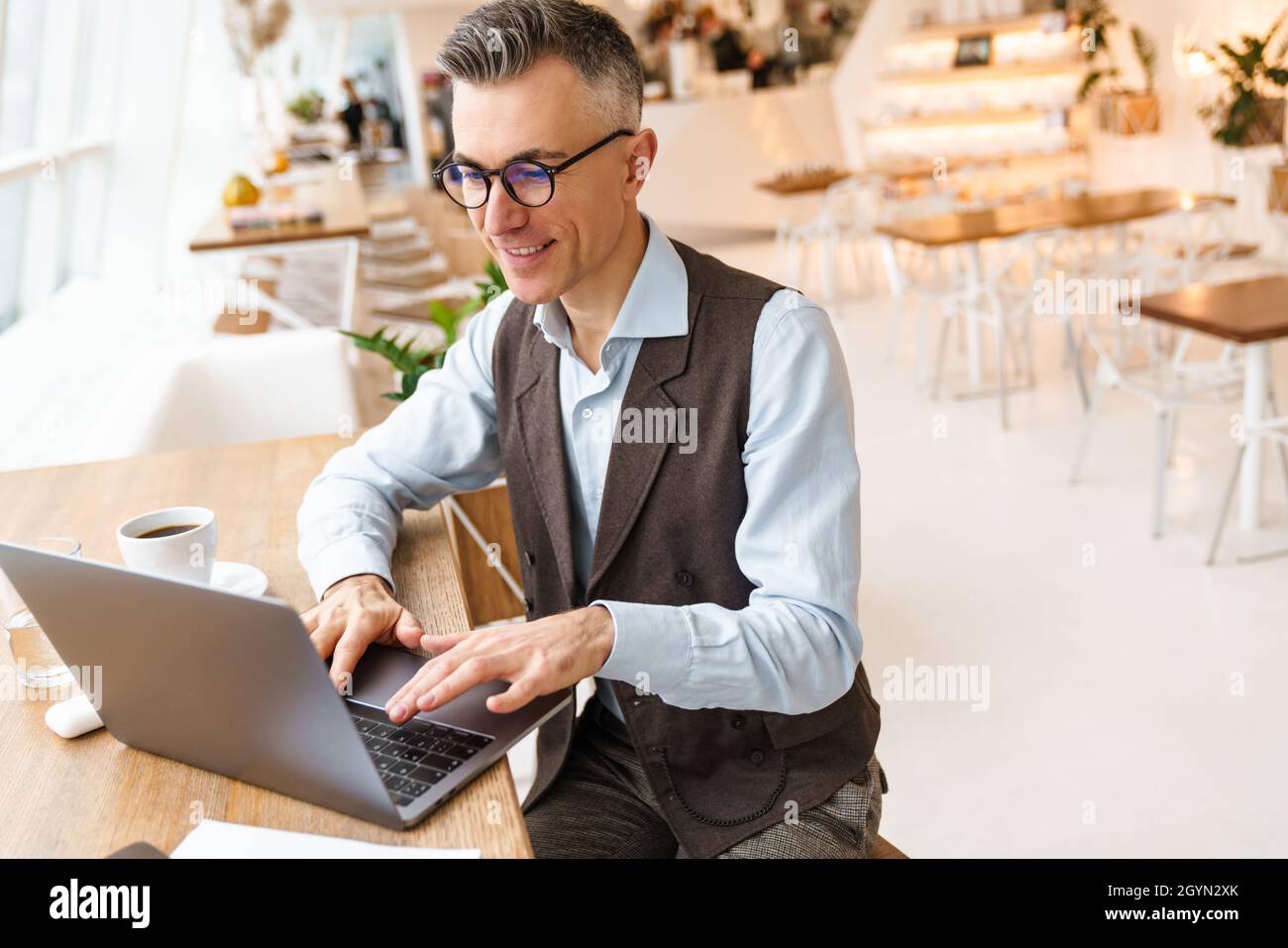 Confident happy handsome businessman in smart clothes working on laptop ...