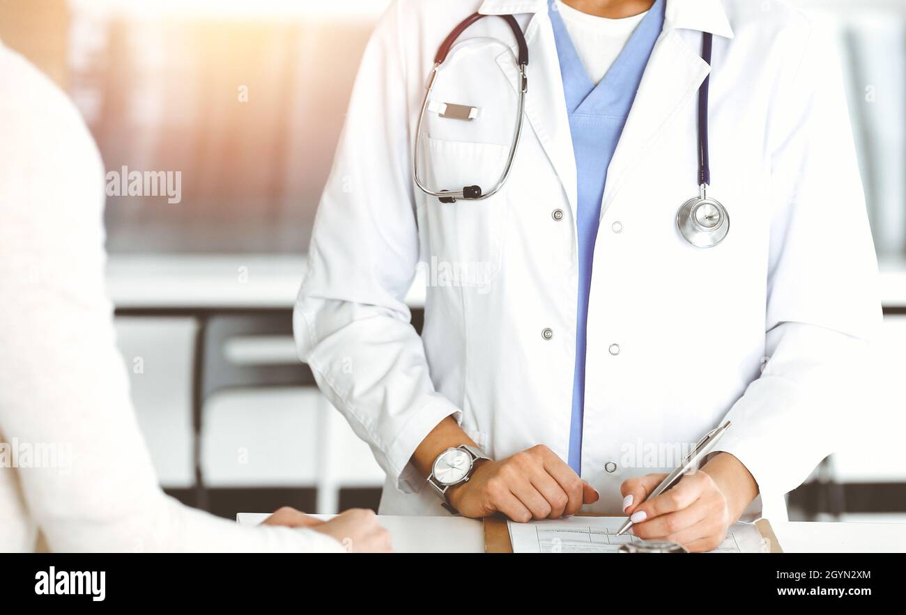 Unknown woman-doctor and patient in sunny hospital. Physician controls ...