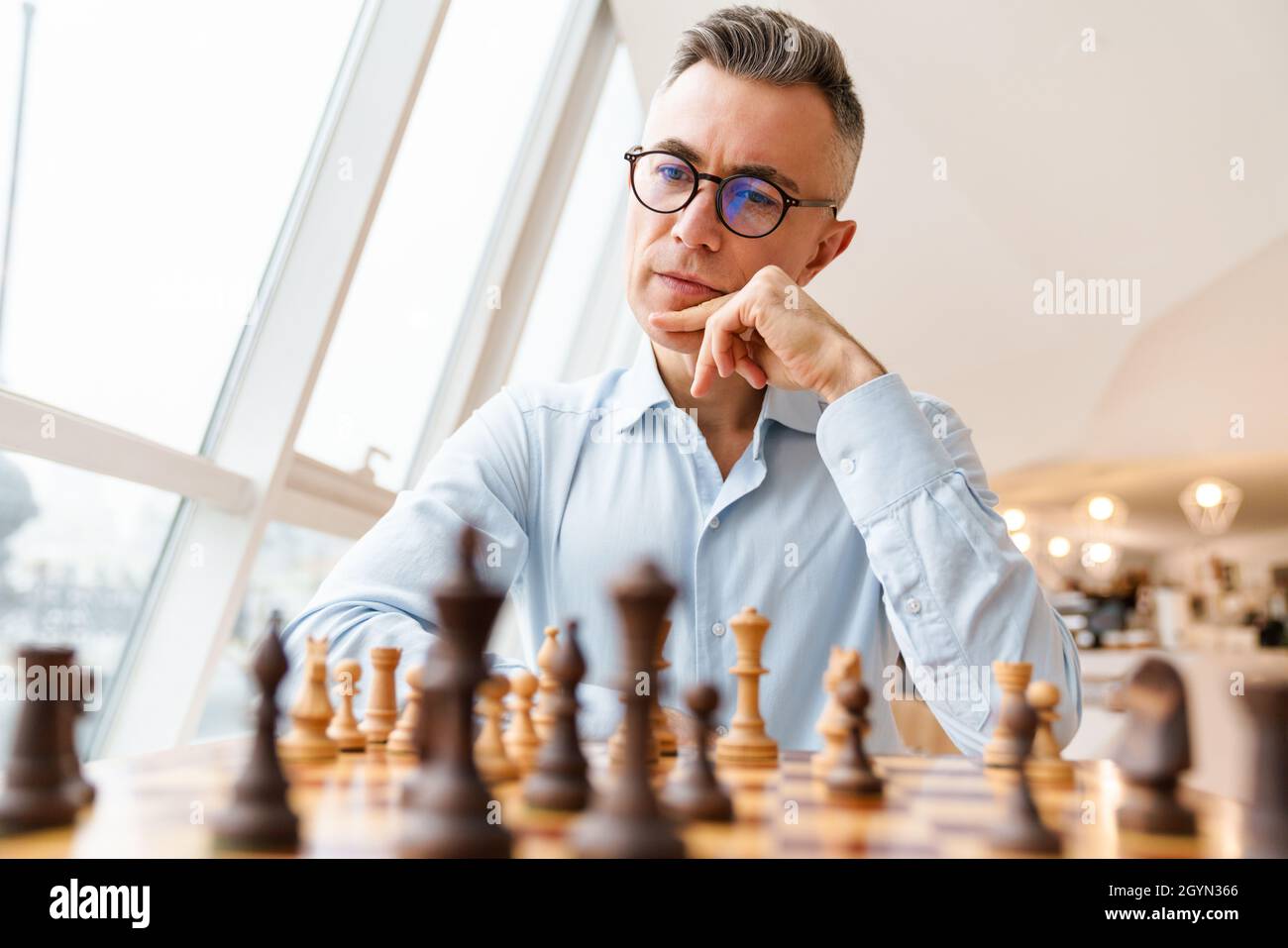 Confident focused business man playing chess indoors Stock Photo - Alamy