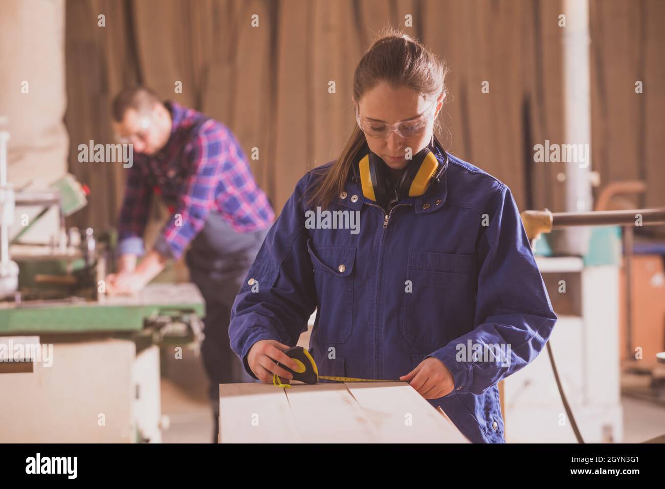Female carpenter focused on measuring wood plank Stock Photo - Alamy