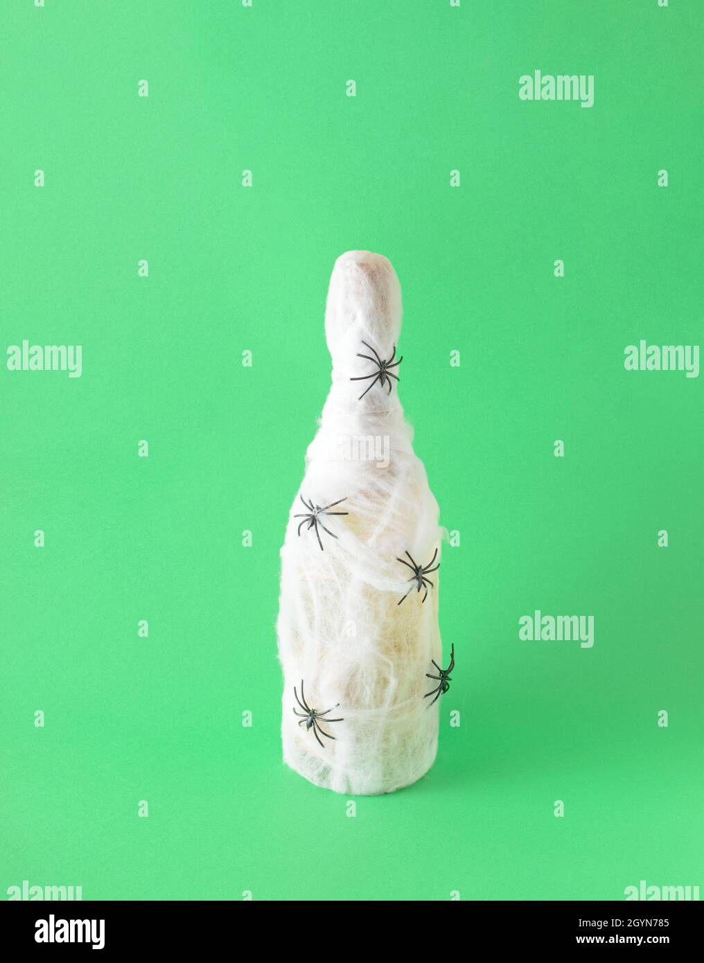 A bottle of champagne in a spider's web. Black spiders stand on the web ...