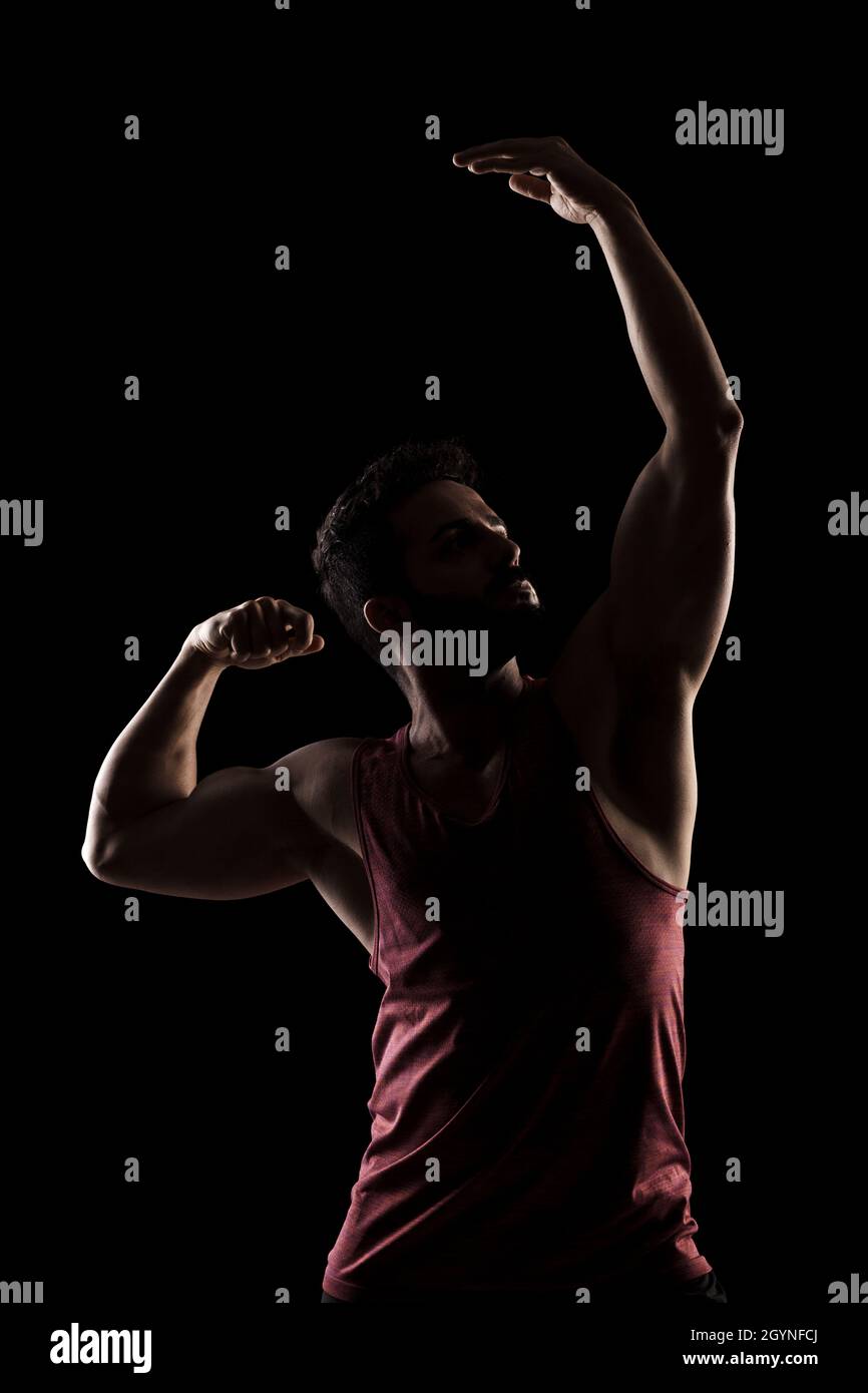 Side lit muscular Caucasian man silhouette. Athlete in red shirt posing ...