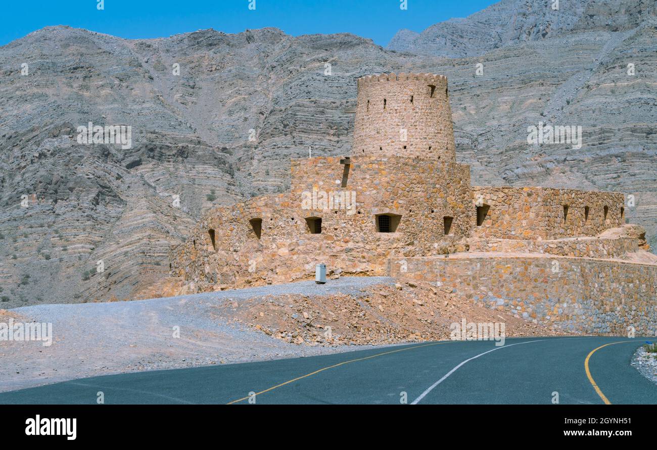 Stone walls of small medieval Arabian fort under tall mountain cliffs ...