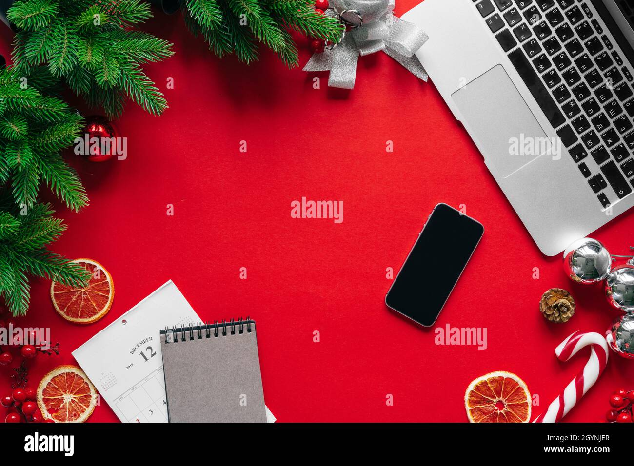 Laptop with fur tree branches and christmas decorations on red ...