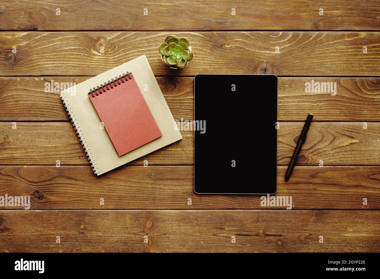 Digital tablet with black screen and notepad and pen on wooden table ...