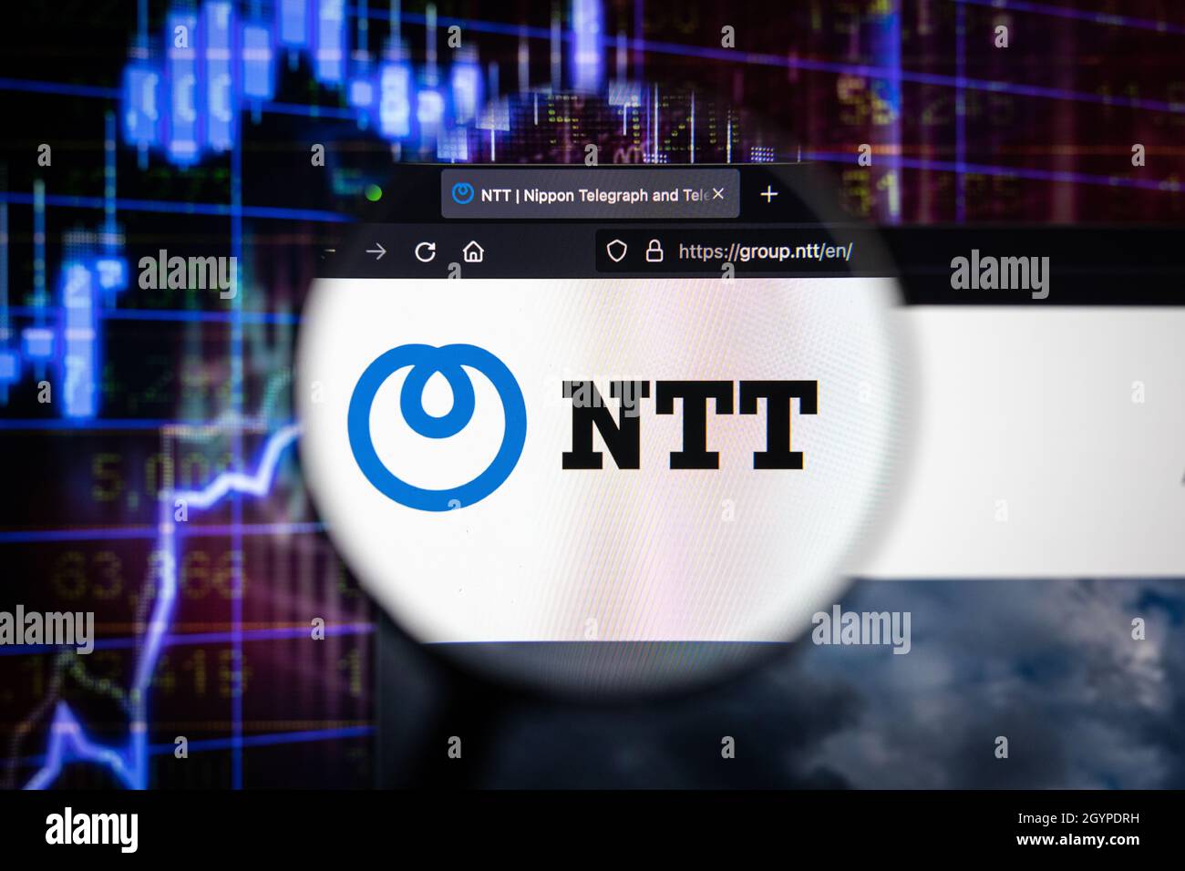 NTT company logo on a website with blurry stock market graphs in the ...