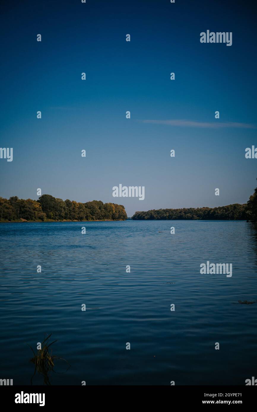 Natural view of a beautiful calm lake and forest under a clear blue sky ...