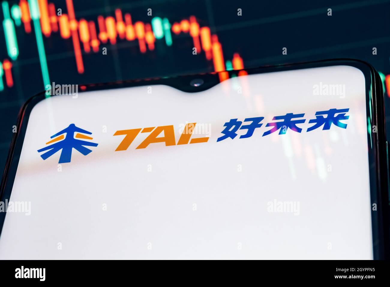 A smartphone with the TAL logo on the background of the stock chart ...