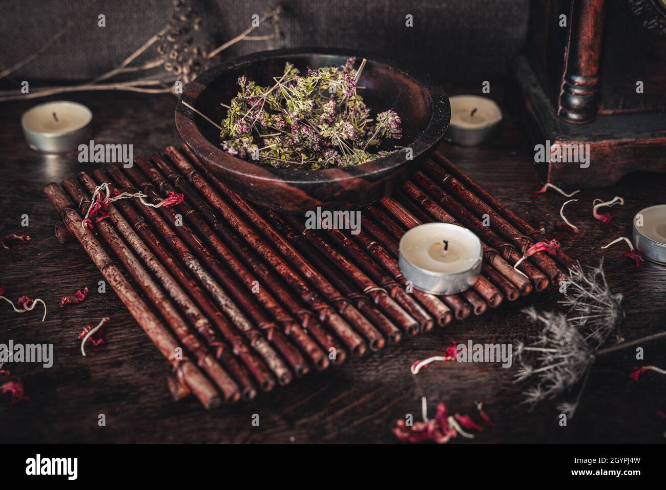 Wooden bowl filled with dried thyme on wiccan witch altar for casting a ...