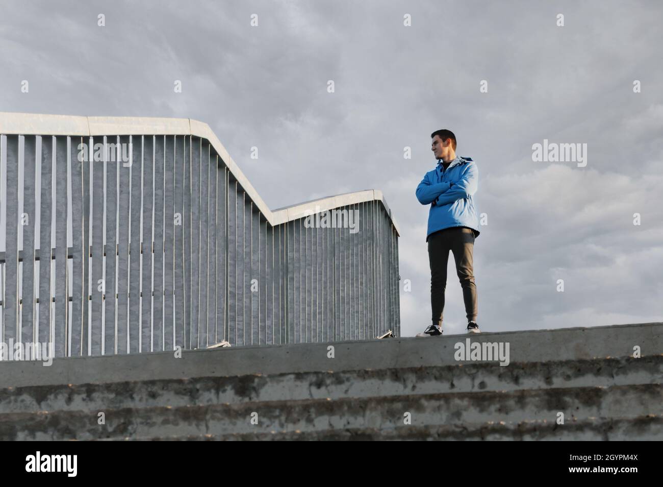 Young man looking into the distance at the gray gloomy cloudy skywhile ...