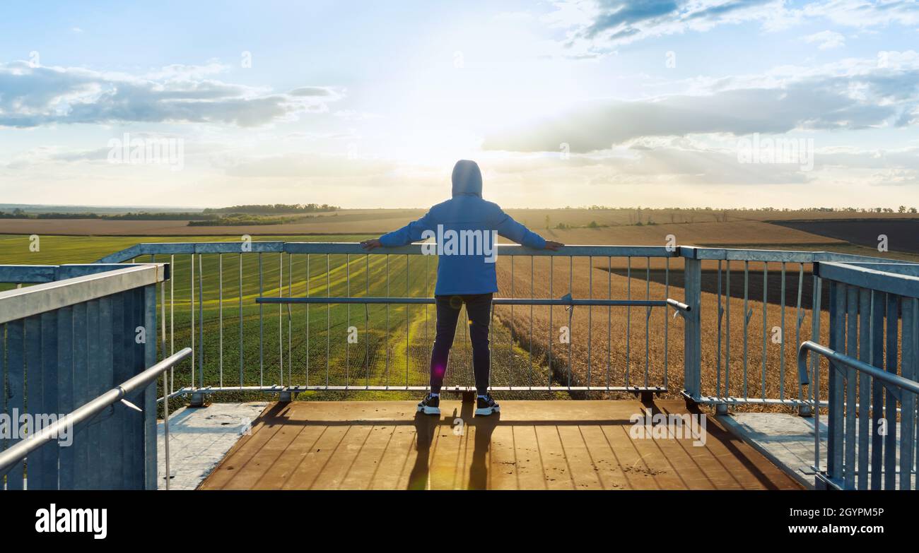 Young sports guy looks at the agricultural fields while standing on the ...