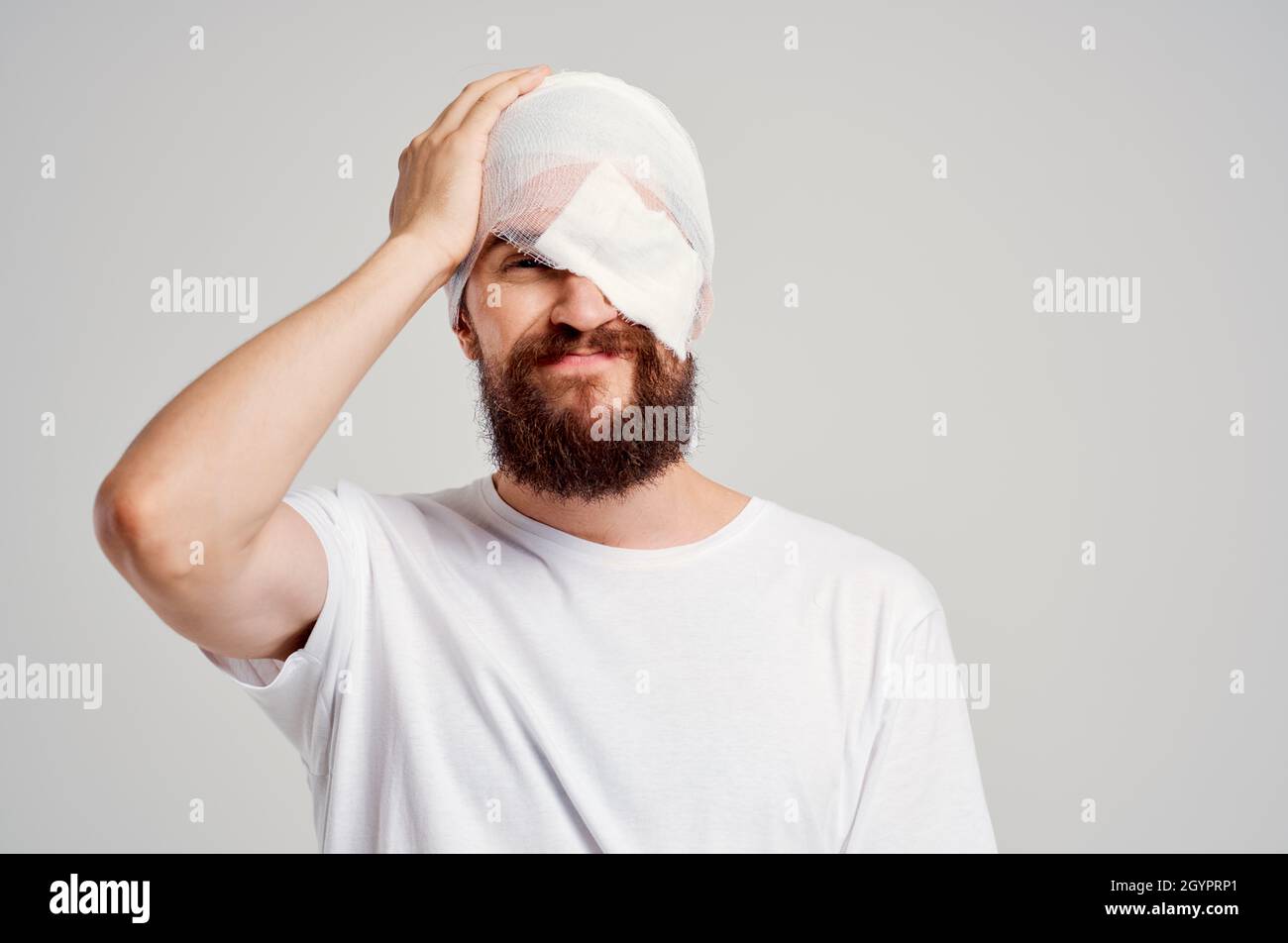 sick man with bandaged head and eye hospitalization light background ...