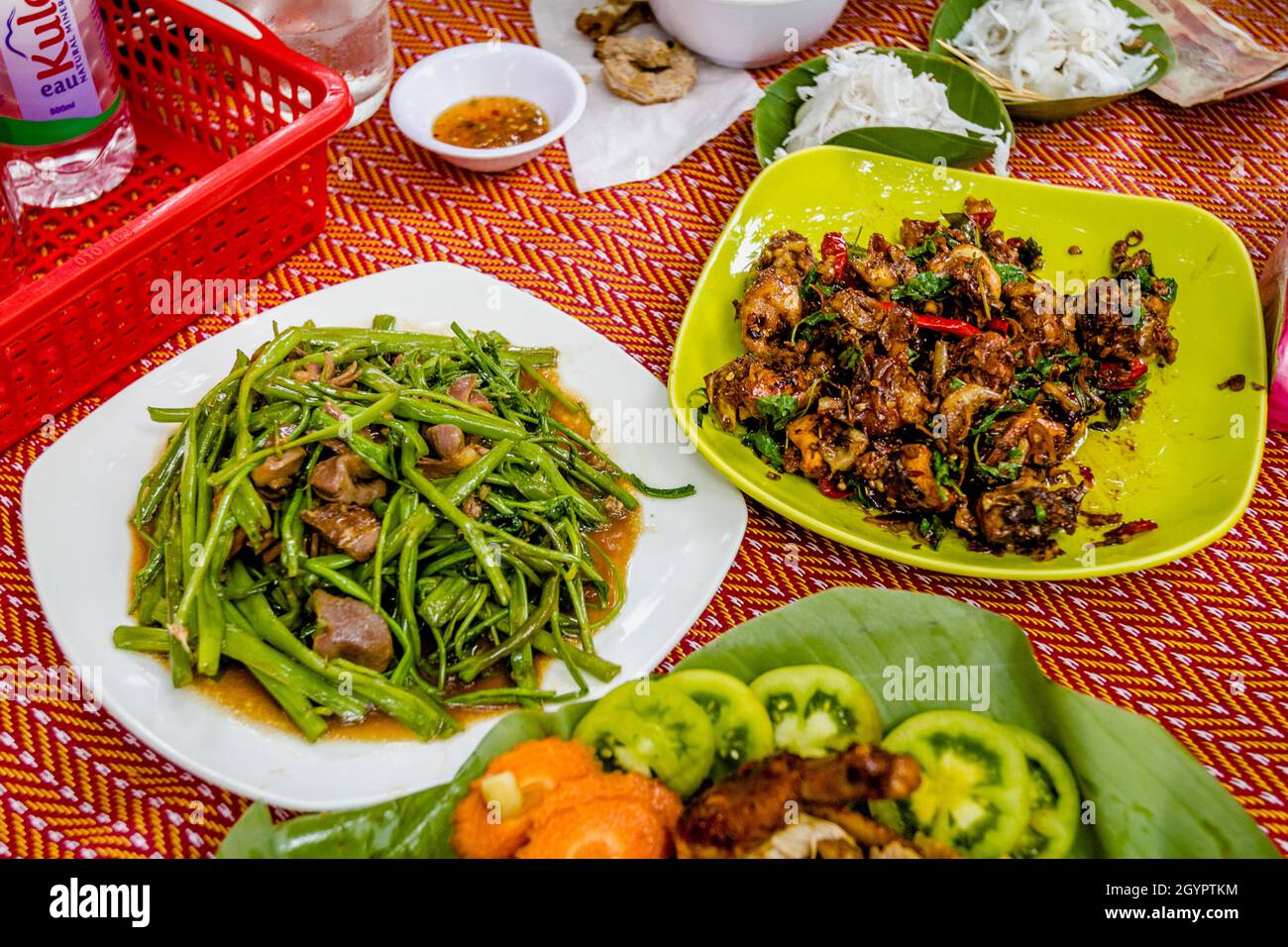 multiple plates of food on covered ground at Khmer restaurant Stock ...