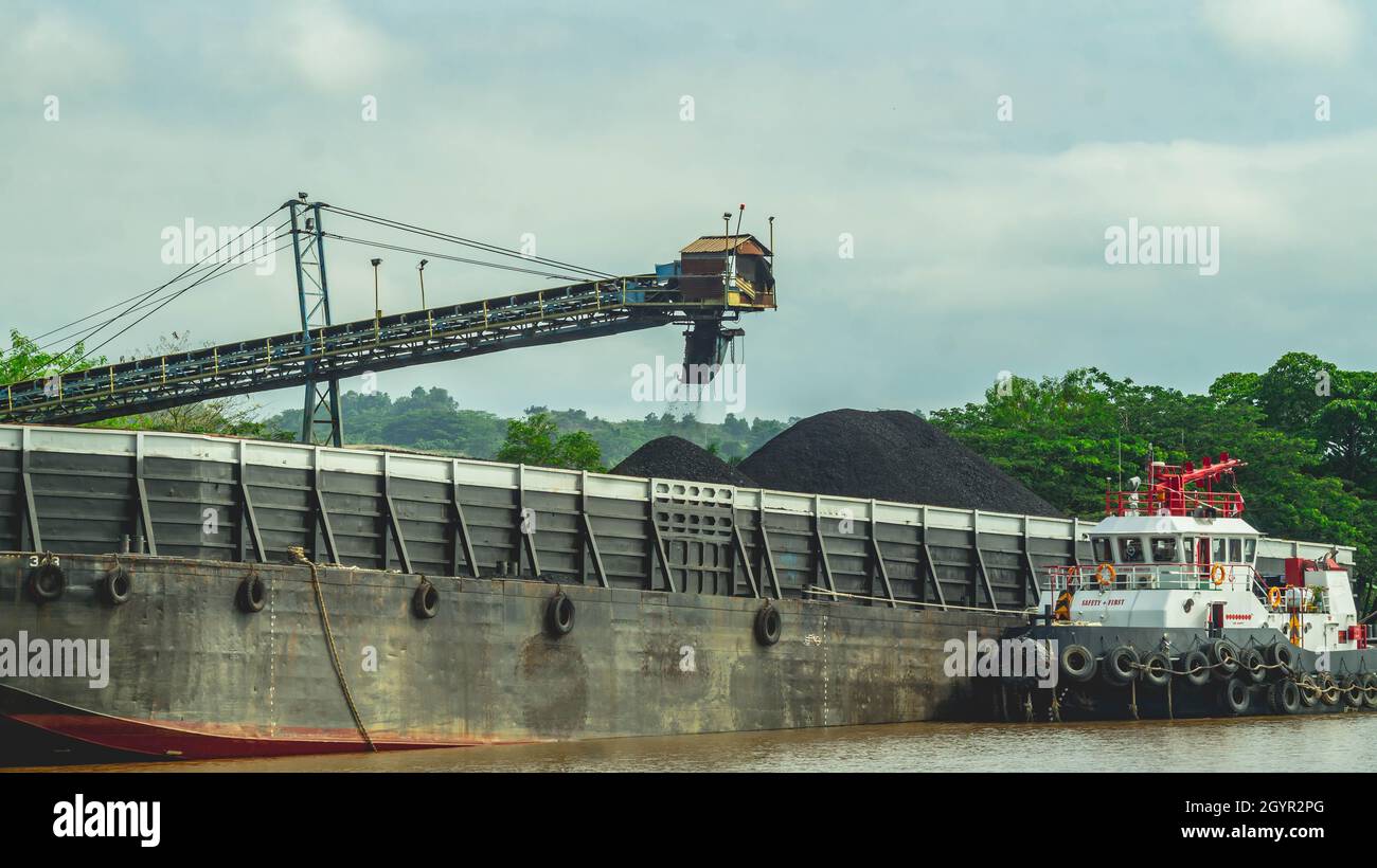 Barge of coal loaded by conveyor, Mahakam River, Outback of Borneo ...