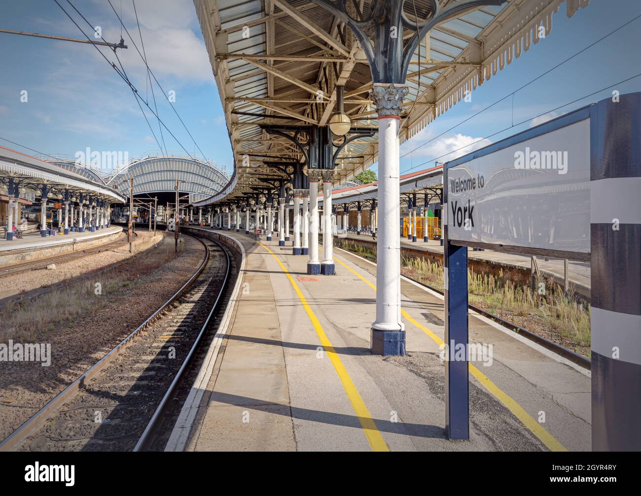 Station welcome sign in blue and white. Shadows fall onto the platform ...